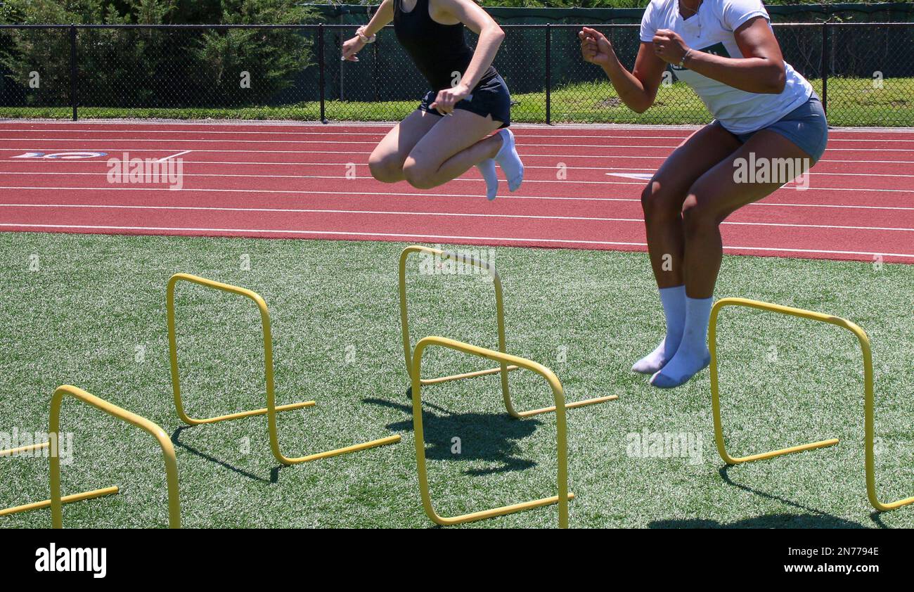 Two twenty something women working our by jumping over two foot tall ...