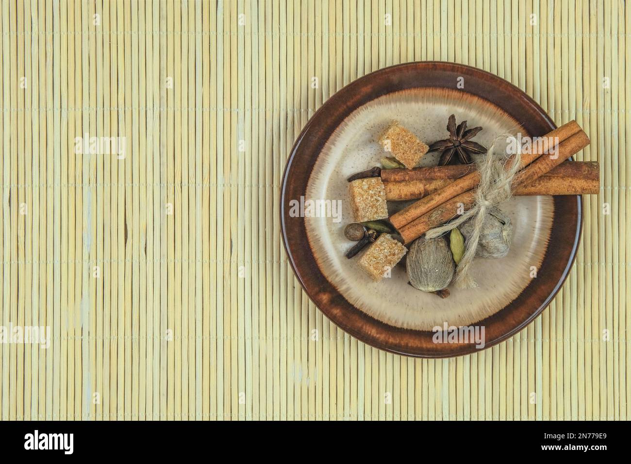 Nutmeg, cinnamon, coriander, anise and cane sugar in a plate on a straw ...