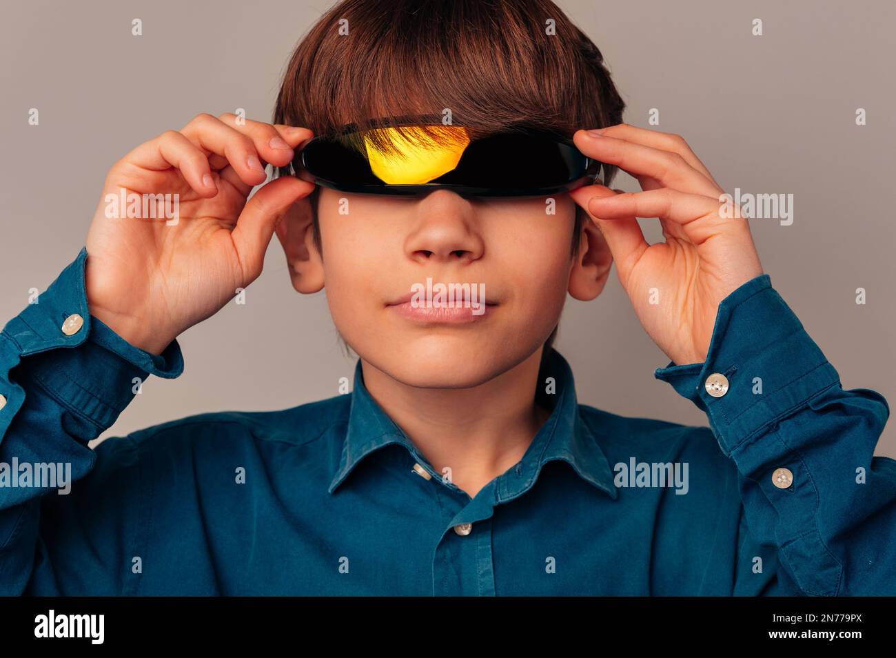 Studio portrait of a serious teen boy wearing blue shirt and cyclops ...