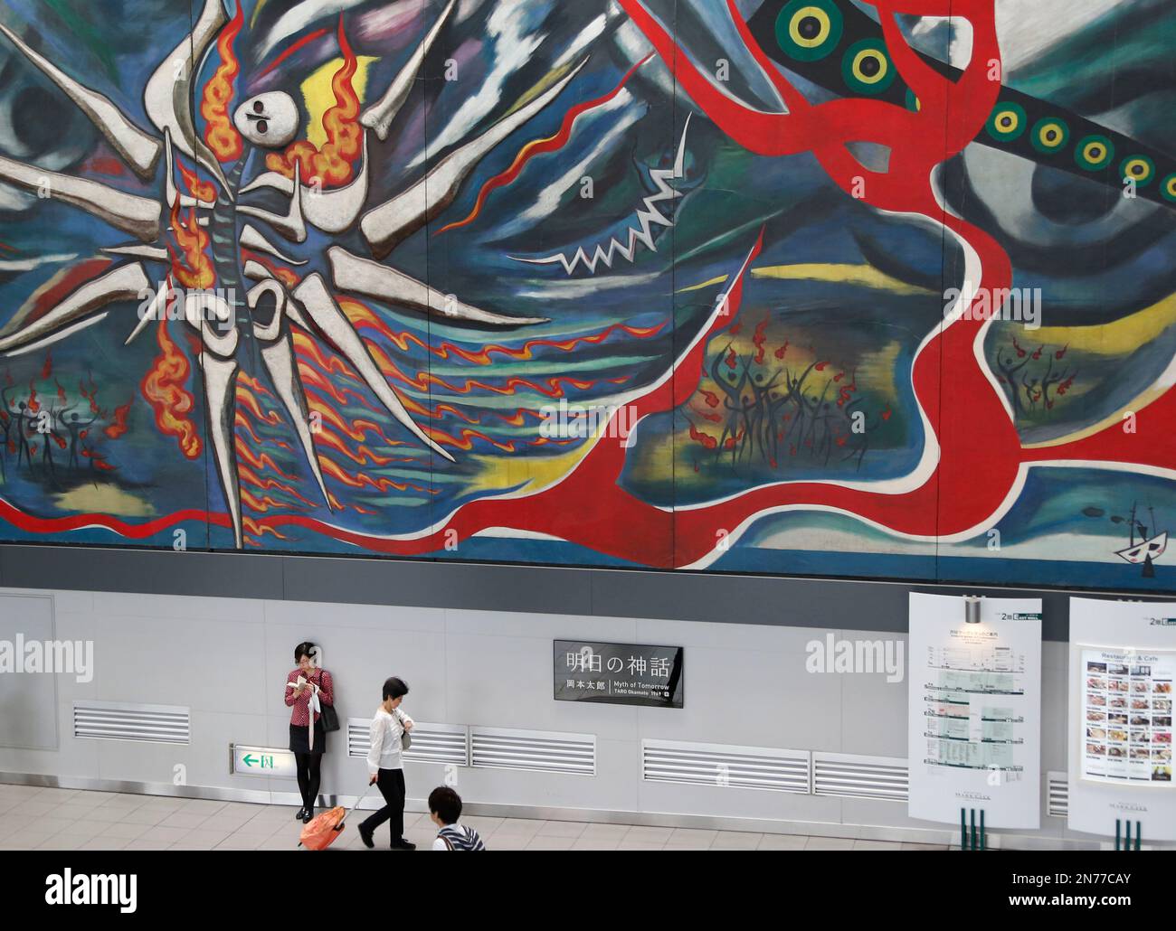 A woman reads a book under a mural by the late Japanese artist Taro ...