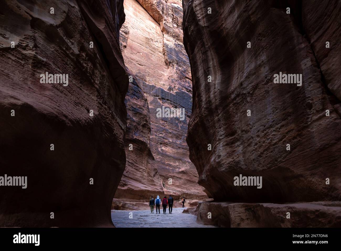 Tourists walk in the Siq canyon in Petra, a famous archaeological site ...