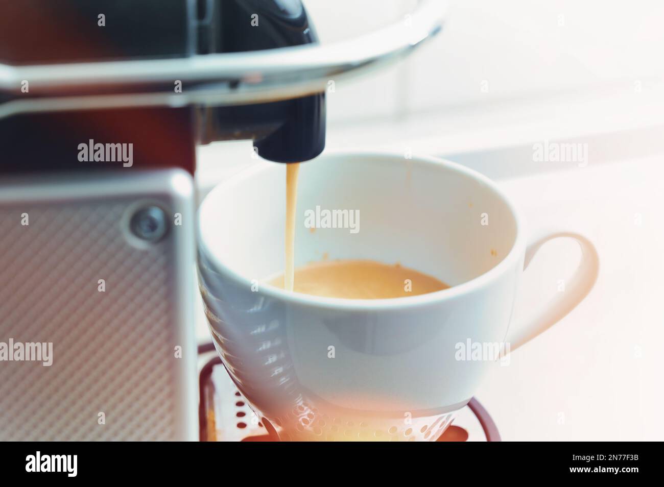 Fresh hot coffee runs out of a modern capsule machine into a white ...