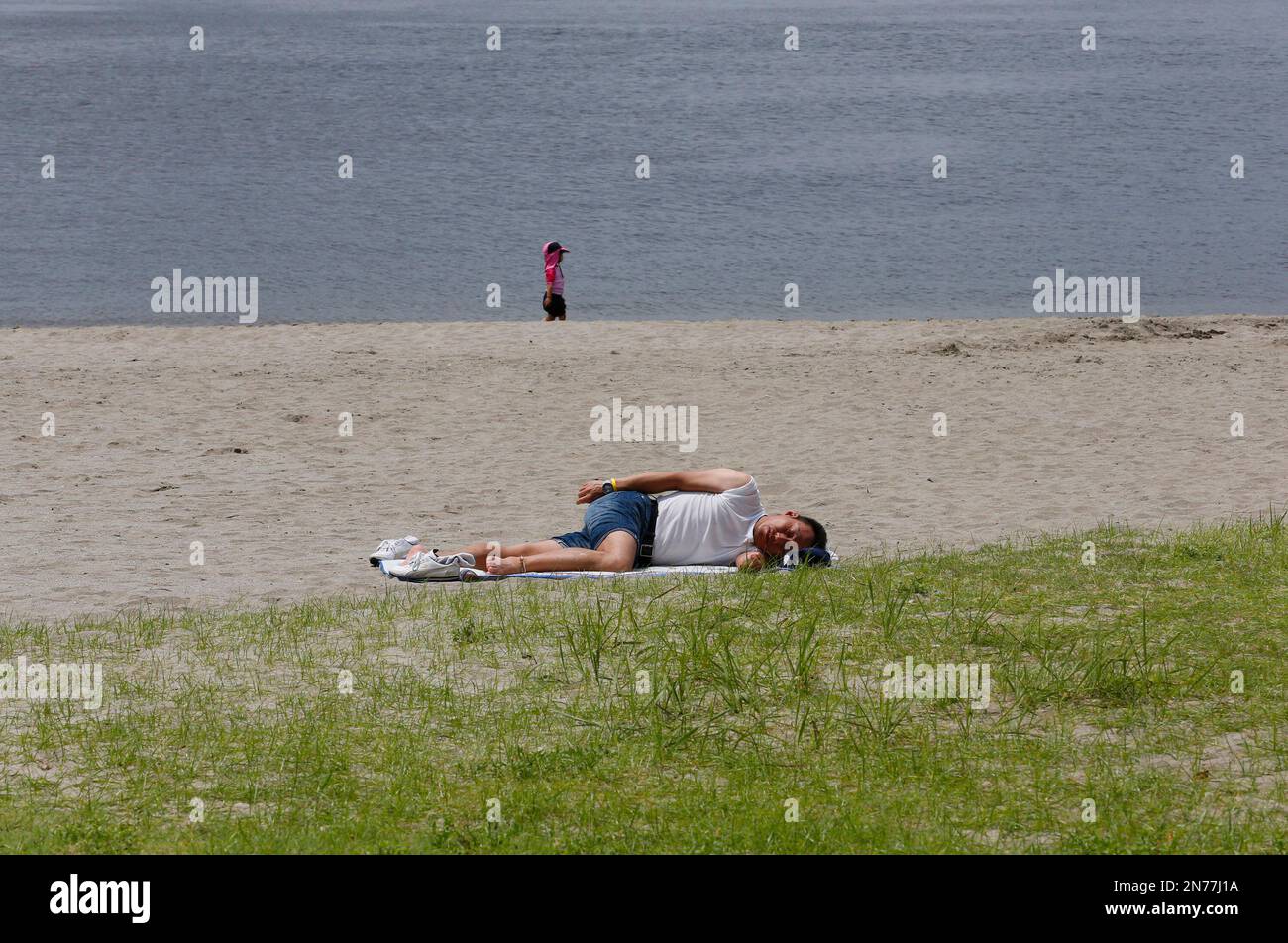 A man takes a nap at a park in Tokyo's Daiba bay area, Sunday, June 30 ...