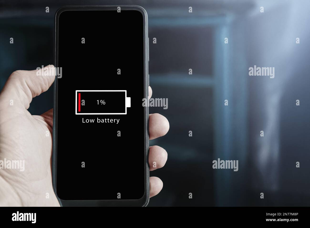 Close up of male hand holding smartphone with low battery icon on the ...
