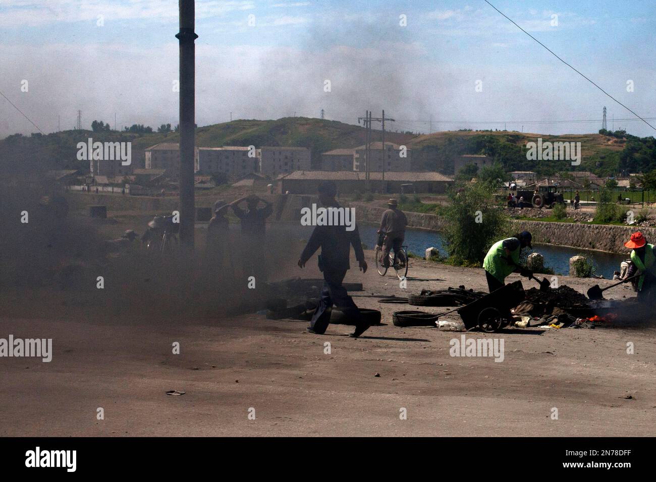 Road workers burn pitch along a road in Haeju city, South Hwanghae ...