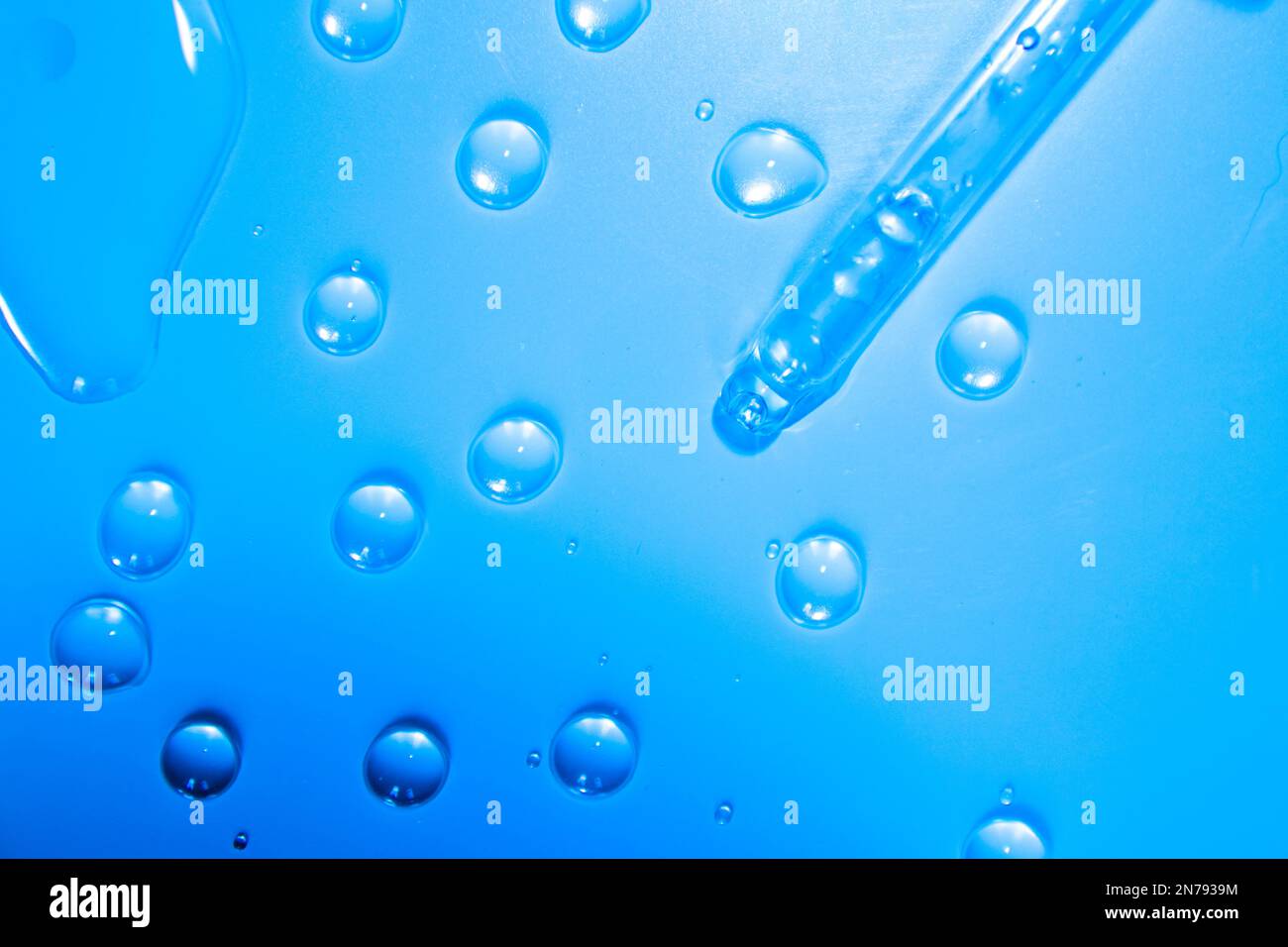 Water bubbles with cosmetic liquid drops of serum on a blue background ...