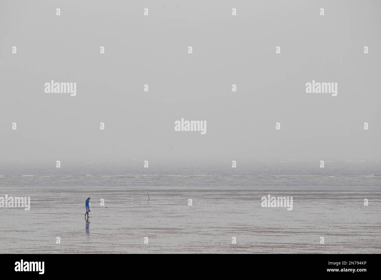 The sky is covered with thick haze as a man walks on a beach in Morib ...