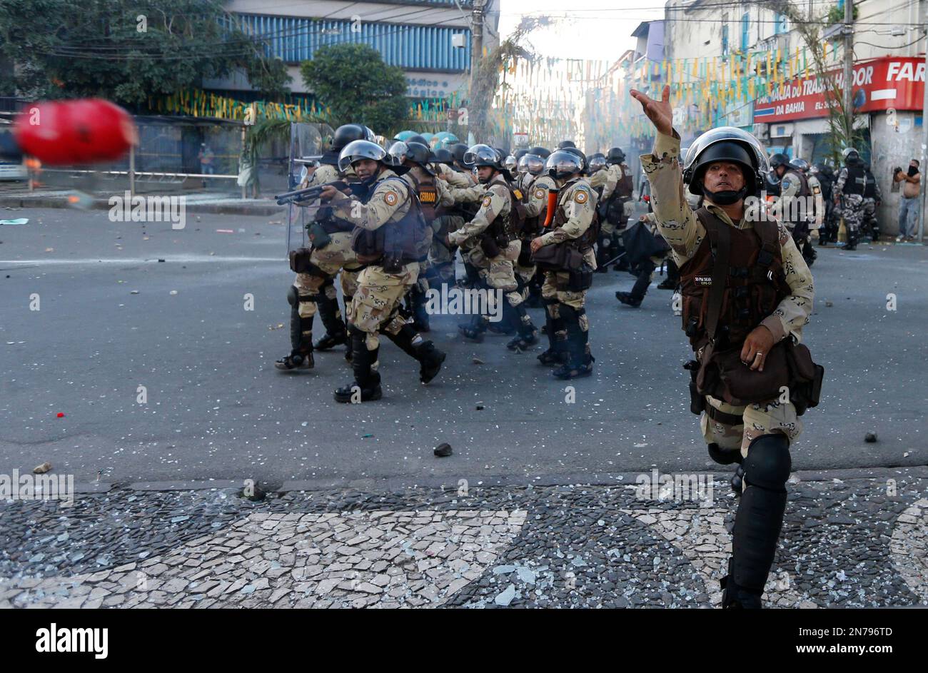 An anti-riot policeman throws a sound grenade to disperse a group of ...