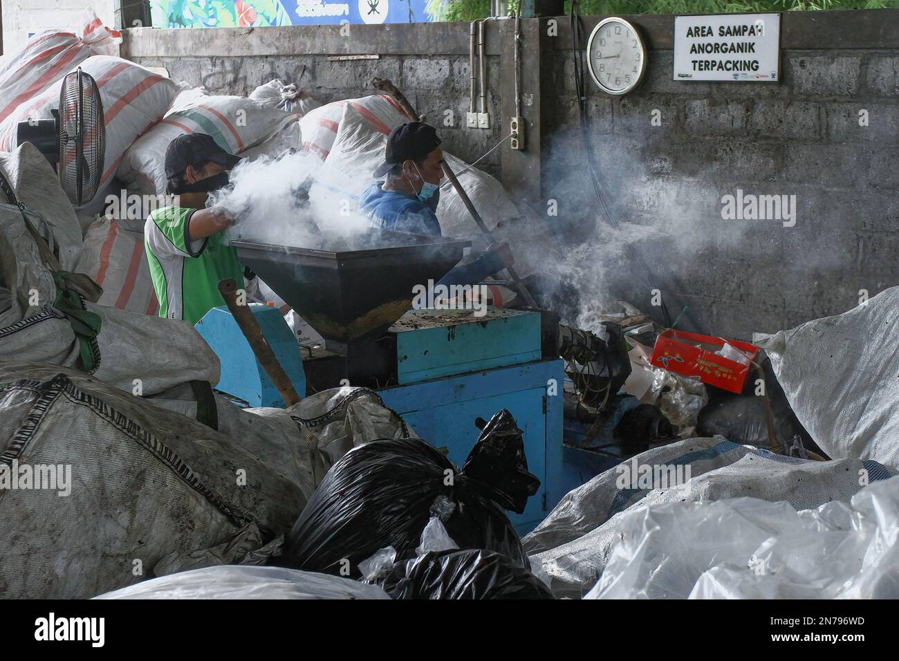 Workers make bricks made from plastic waste at a waste management site ...