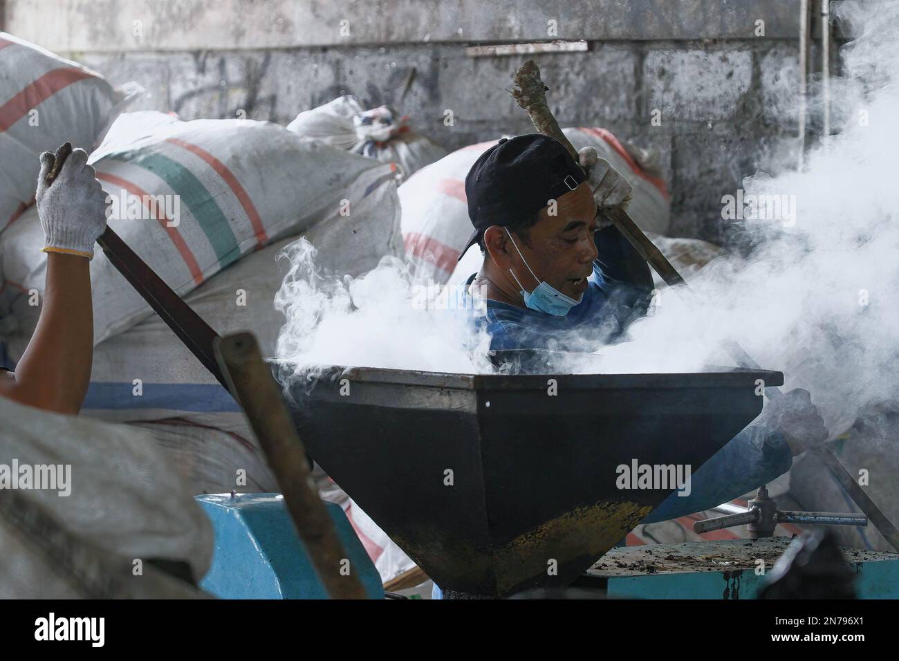 Workers make bricks made from plastic waste at a waste management site ...