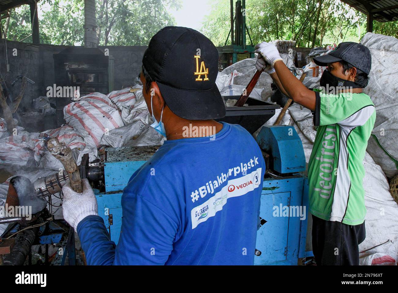 Workers make bricks made from plastic waste at a waste management site ...