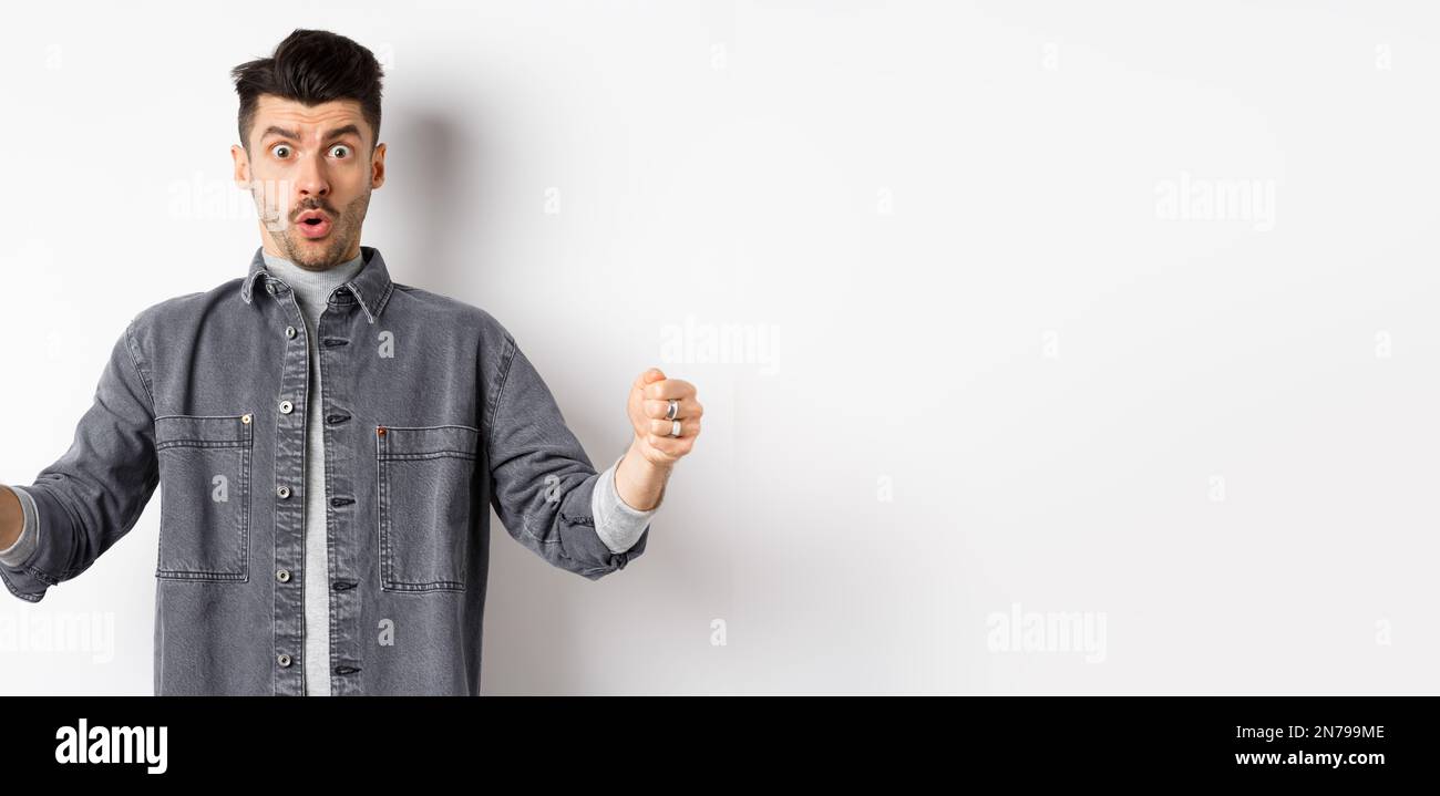 Confused man holding big size object and looking shocked, shaping large ...