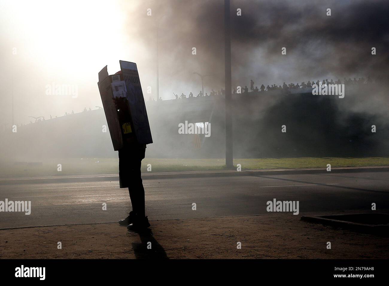 A protestor uses a cardboard box as a shield against rubber bullets ...