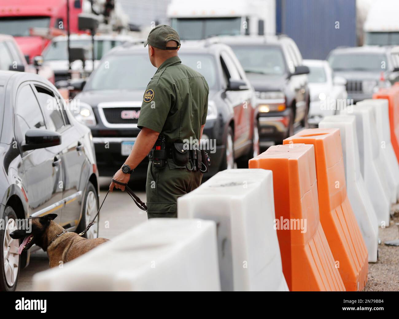 A U.S. Customs and Border Patrol agent and K-9 security dog keep watch ...