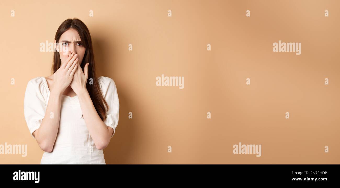 Shocked and confused woman frowning upset, covering mouth with hands ...