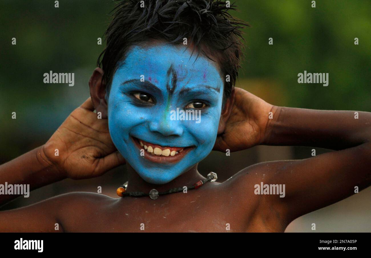 A young Indian boy with his face painted as Hindu god Shiva reacts to ...