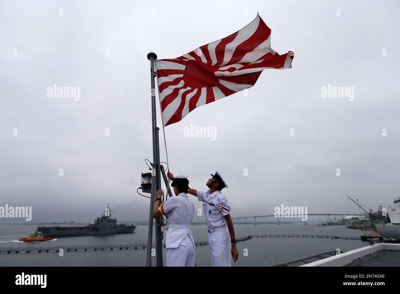 Japanese sailors raise their naval ensign aboard the JS Hyuga destroyer ...