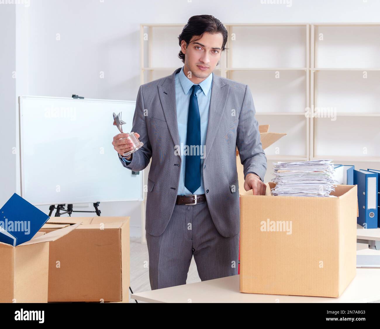 The young man employee with boxes in the office Stock Photo - Alamy