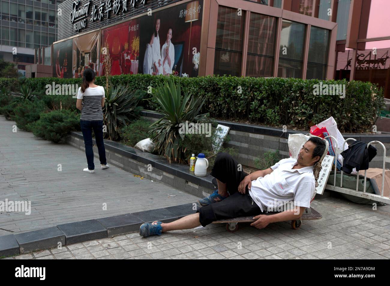 A Chinese man waiting to recollect recyclable waste material naps on a ...