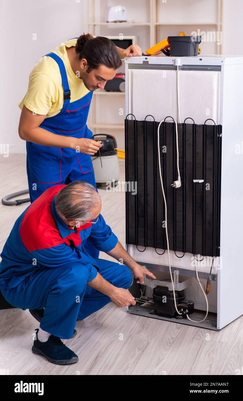The two contractors repairing fridge at workshop Stock Photo - Alamy
