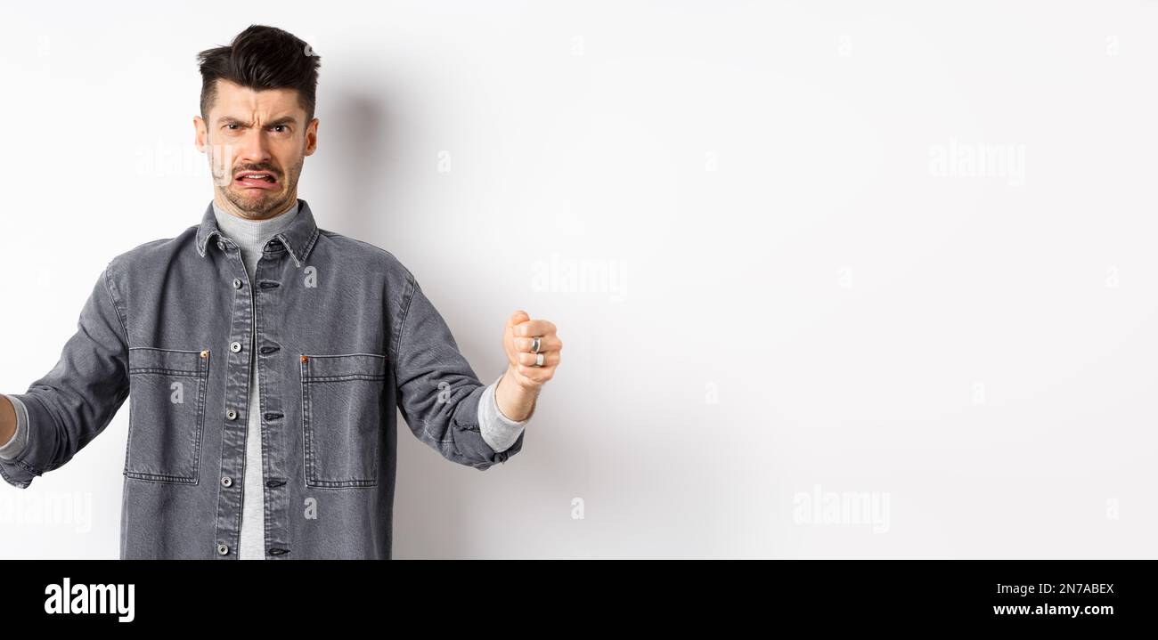 Disgusted guy showing big size object and grimacing from dislike and ...