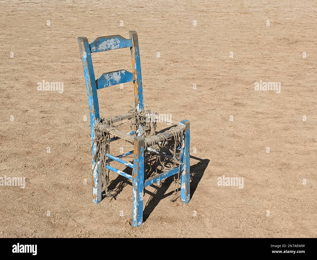 An old weathered chair with ropes on a sandy ground Stock Photo - Alamy