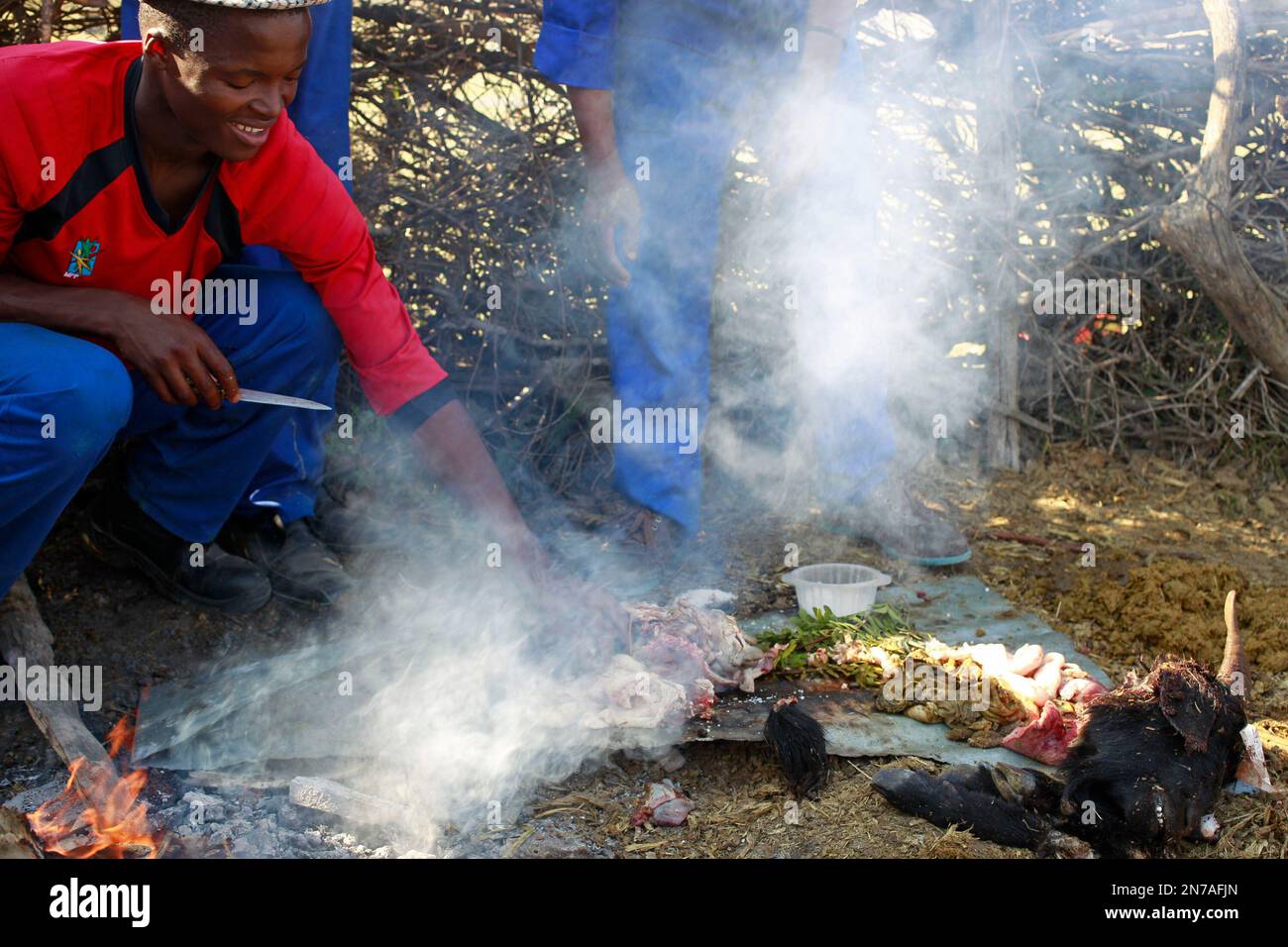 Family members of Xhosa tribe member Baba Mfundisi grill goat meat ...