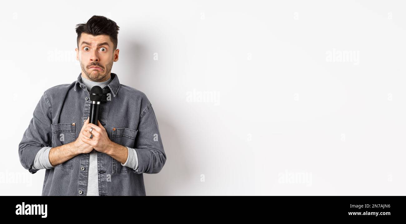 Nervous unconfident guy holding microphone and look indecisive, scared ...
