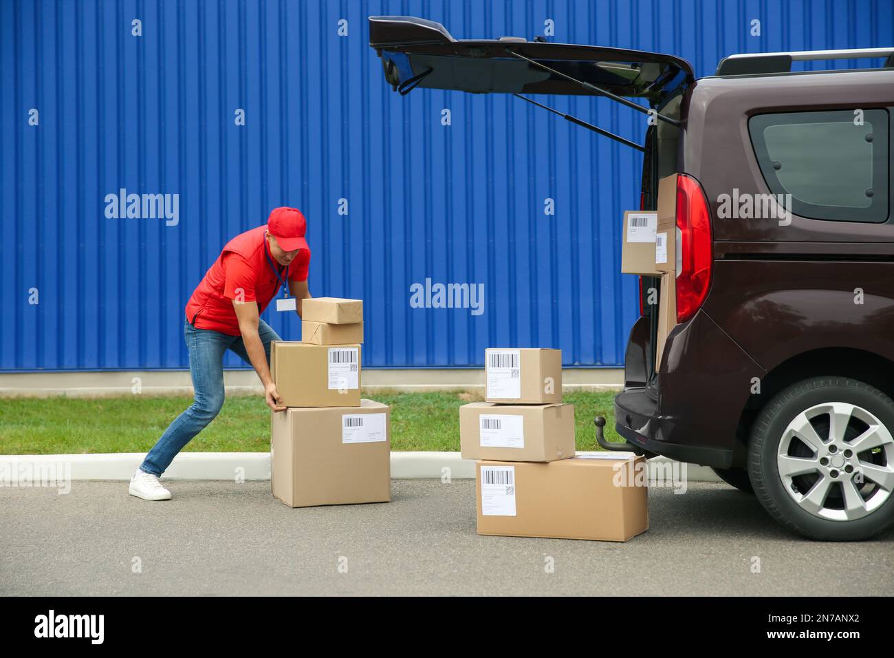 Courier loading packages in car trunk outdoors Stock Photo - Alamy