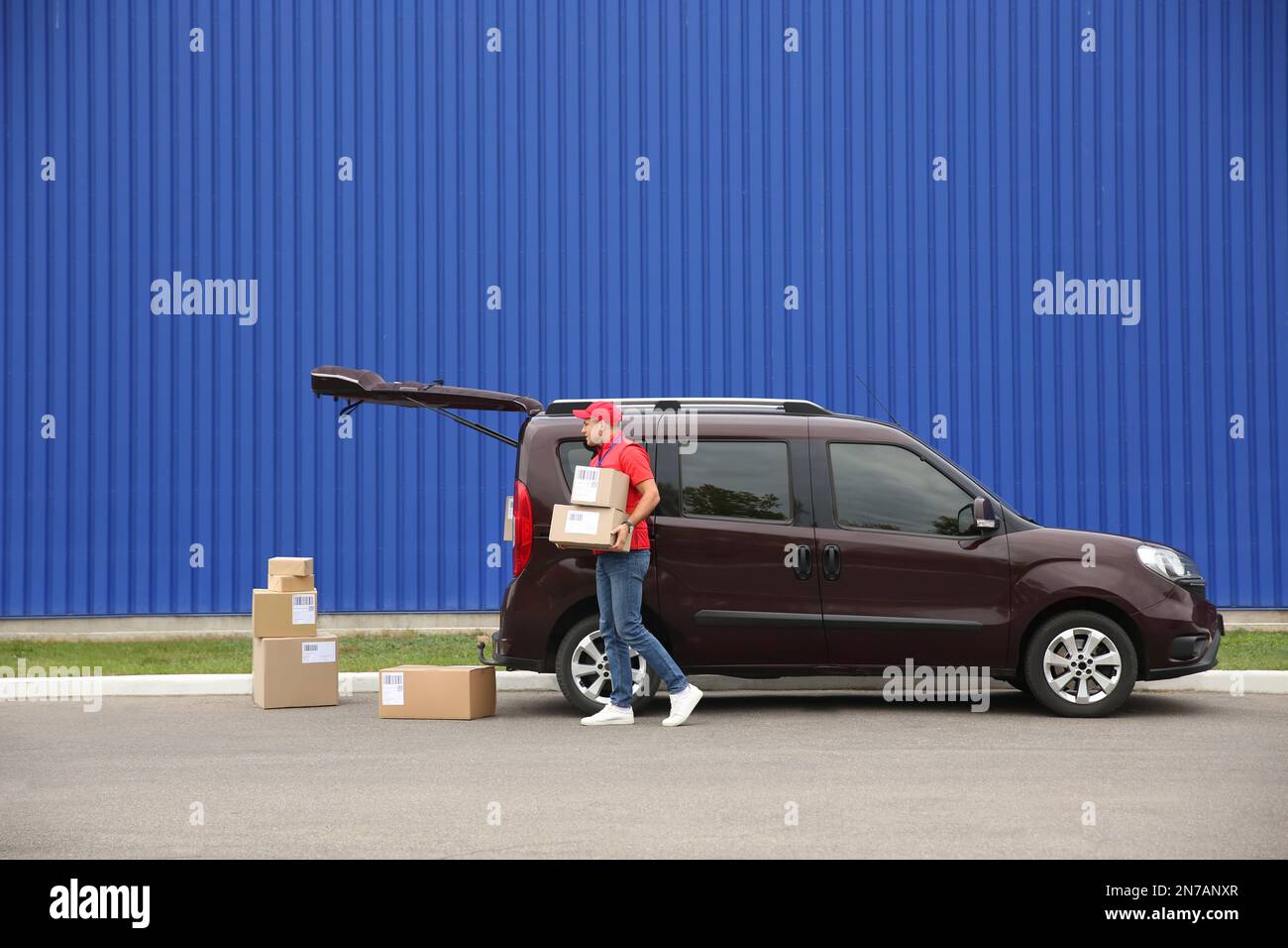 Courier loading packages in car outdoors, space for text Stock Photo ...