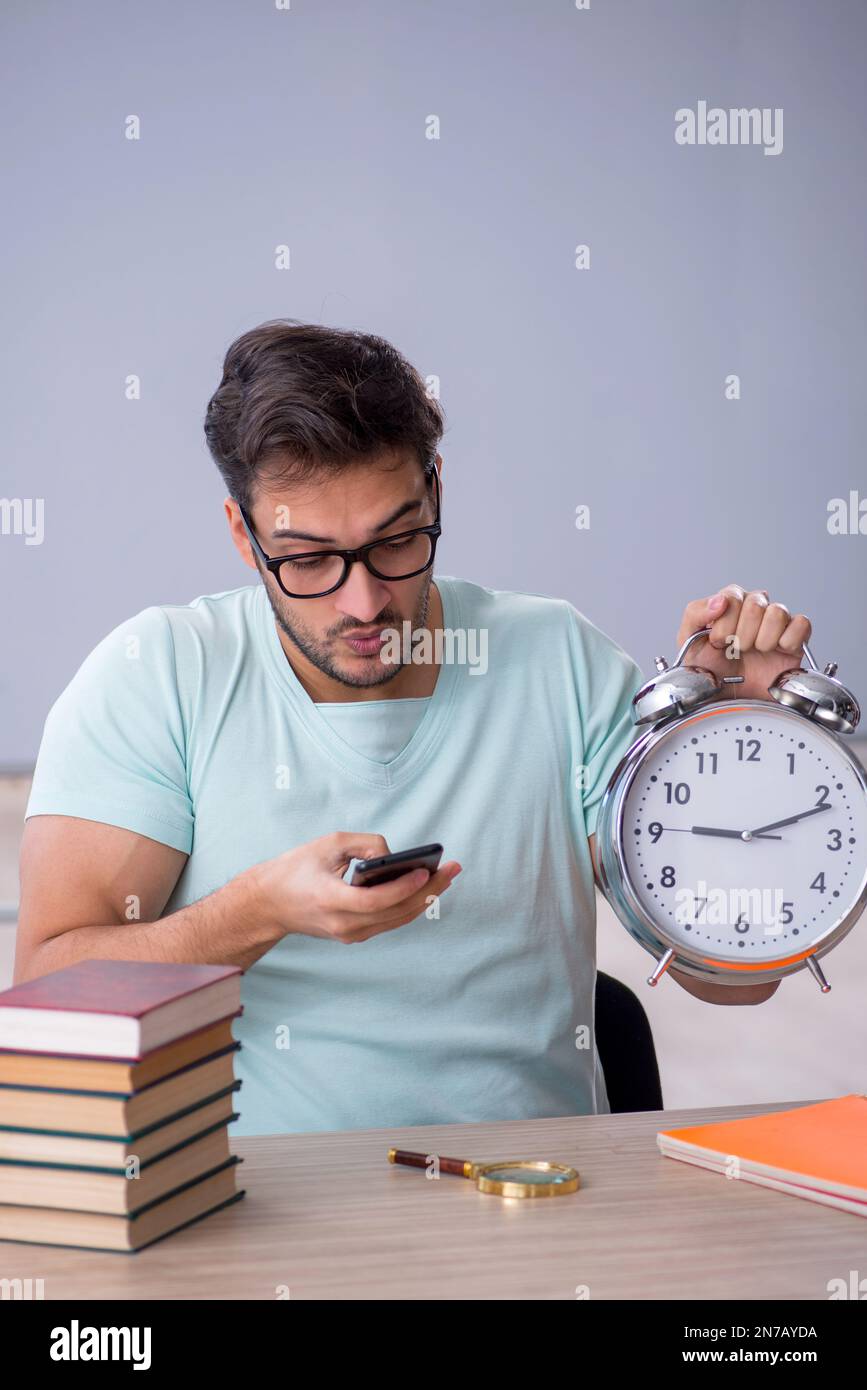 Young student in time management concept in the classroom Stock Photo ...