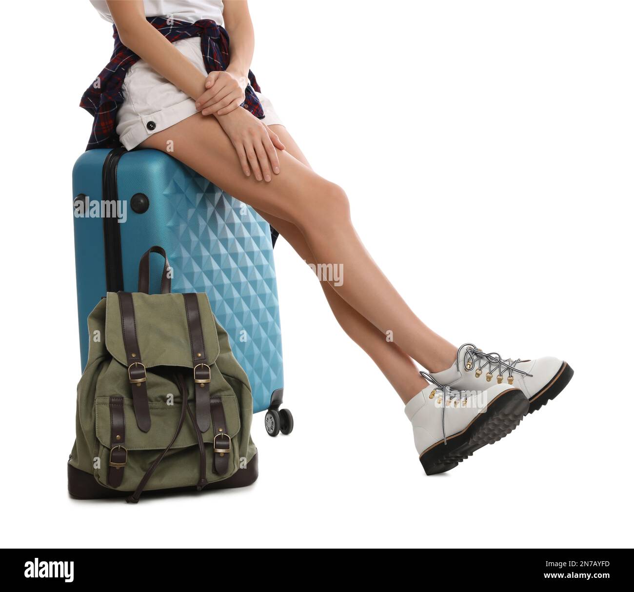 Woman sitting on suitcase near backpack against white background ...