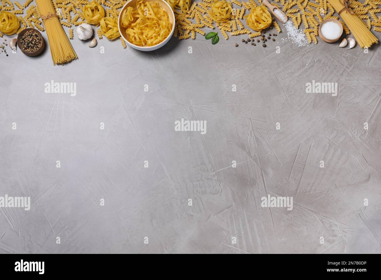 Flat lay composition with different types of pasta on grey table, space ...