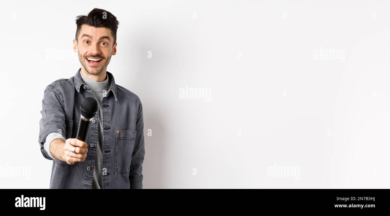 Handsome smiling man stretch out hand with microphone, giving you mic ...