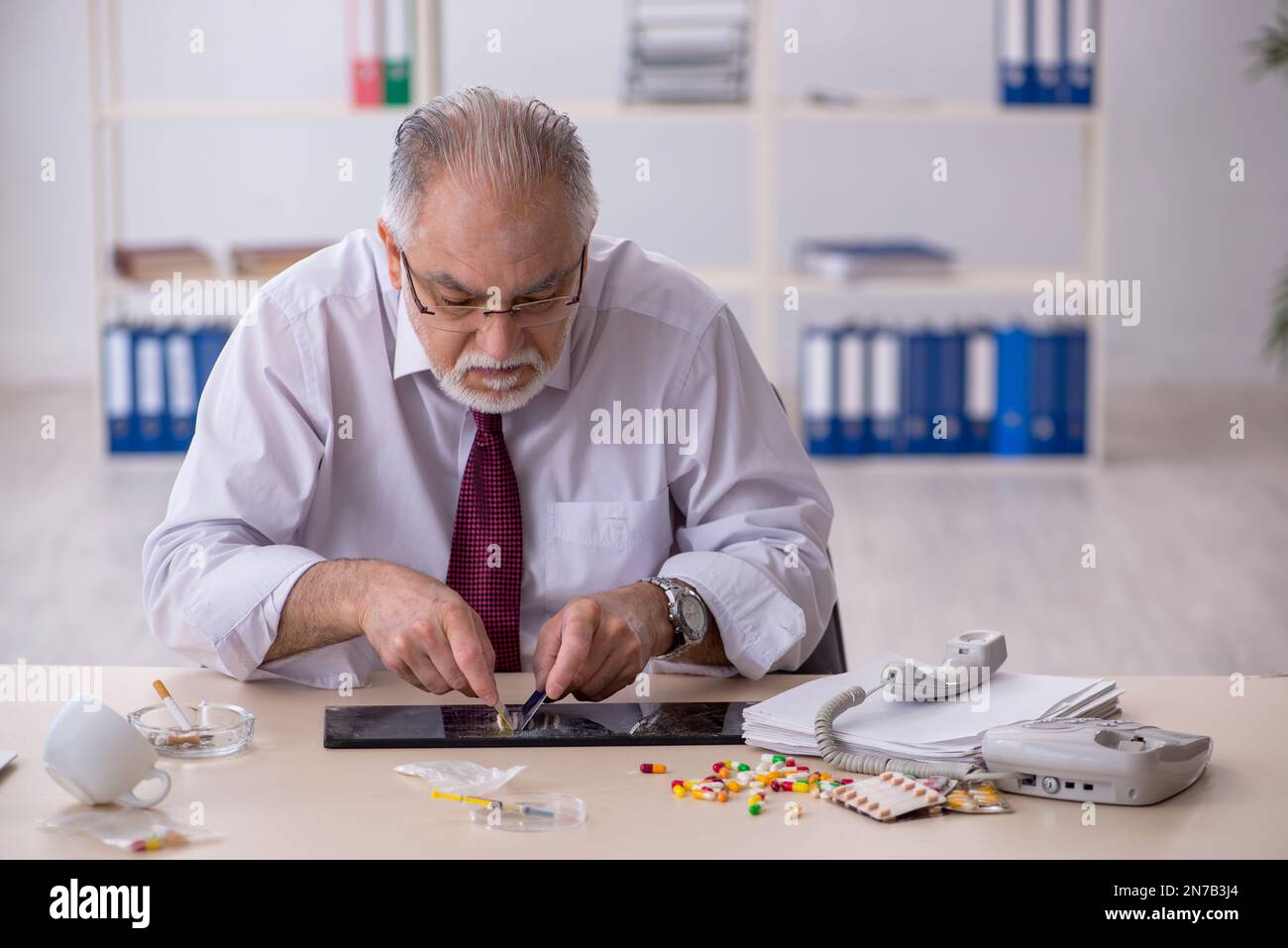 Old male drug addicted employee sitting at workplace Stock Photo - Alamy