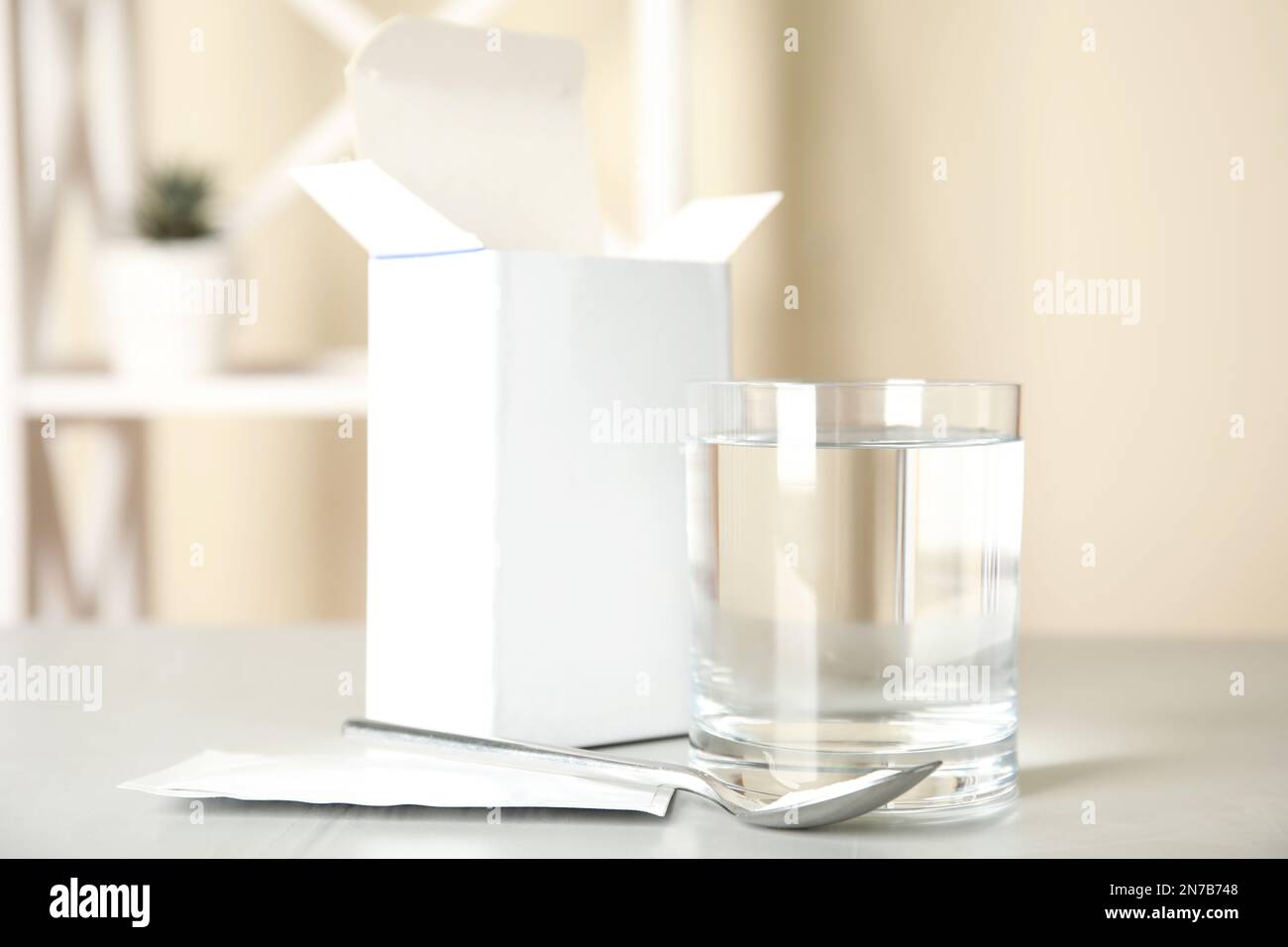 Medicine sachet, glass of water and spoon on light table Stock Photo ...