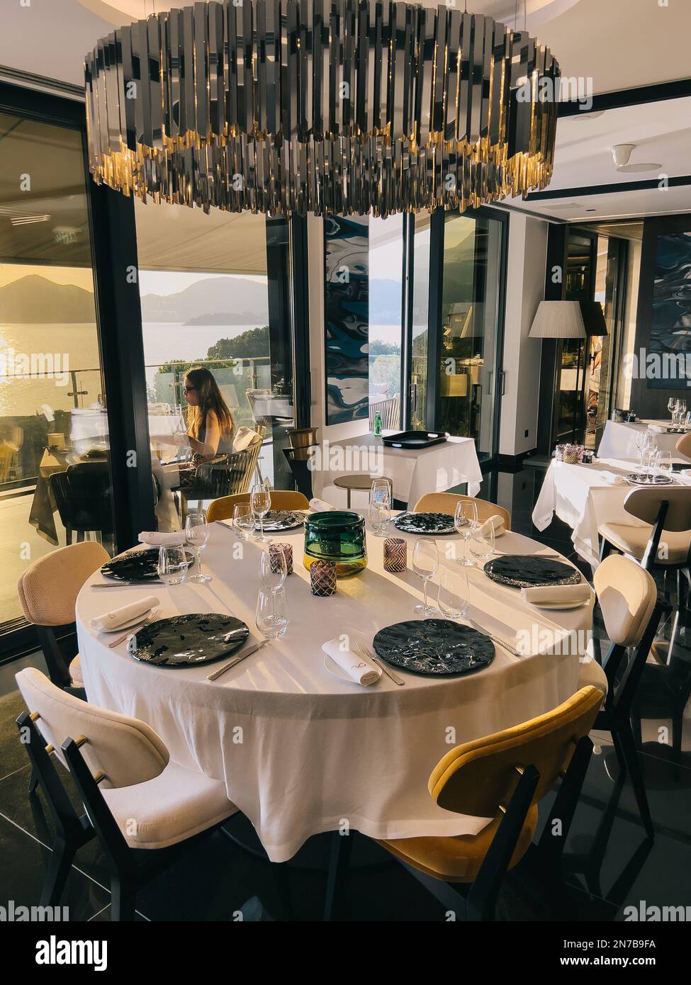 Large chandelier hangs over a set round table in a restaurant Stock ...