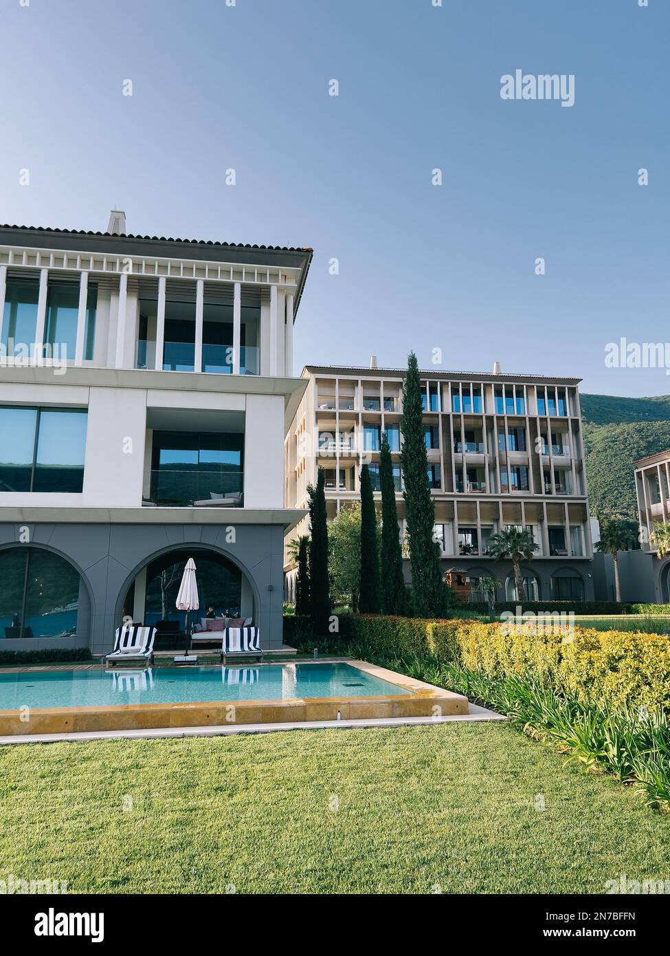 Swimming pool on the green lawn in front of the hotel with terraces and ...
