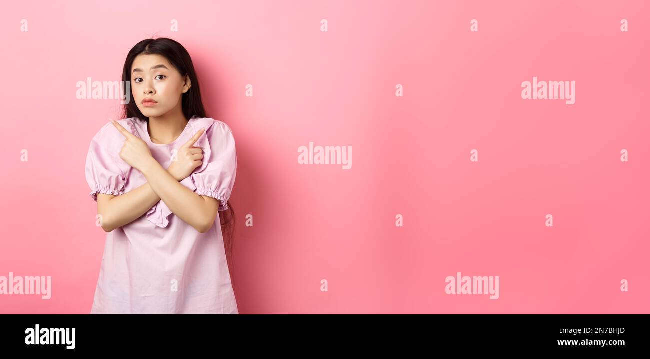 Clueless cute asian girl pointing sideways and look confused, cant make ...