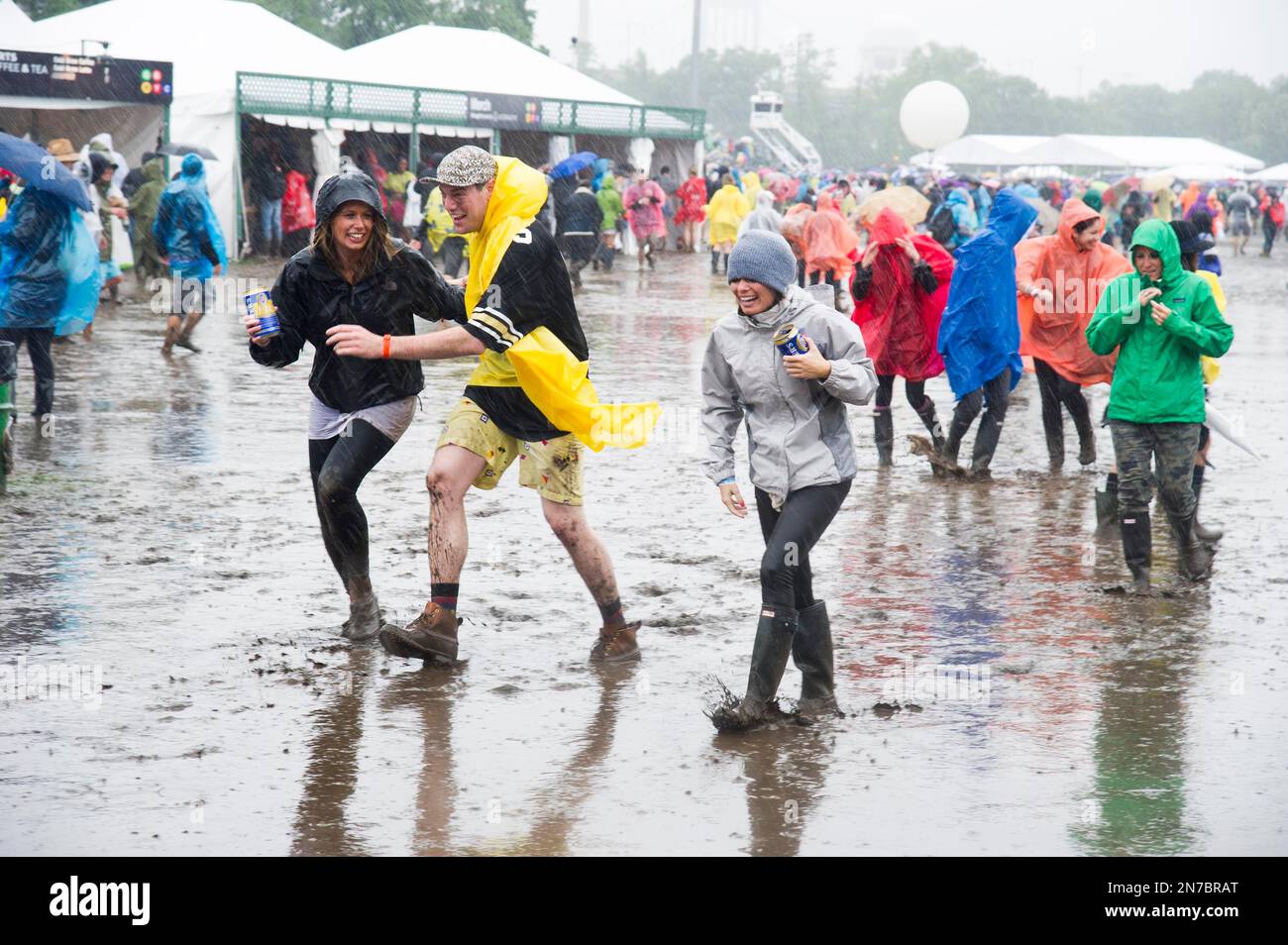 Concertgoers walk through a field of mud at the rain soaked 3rd annual ...