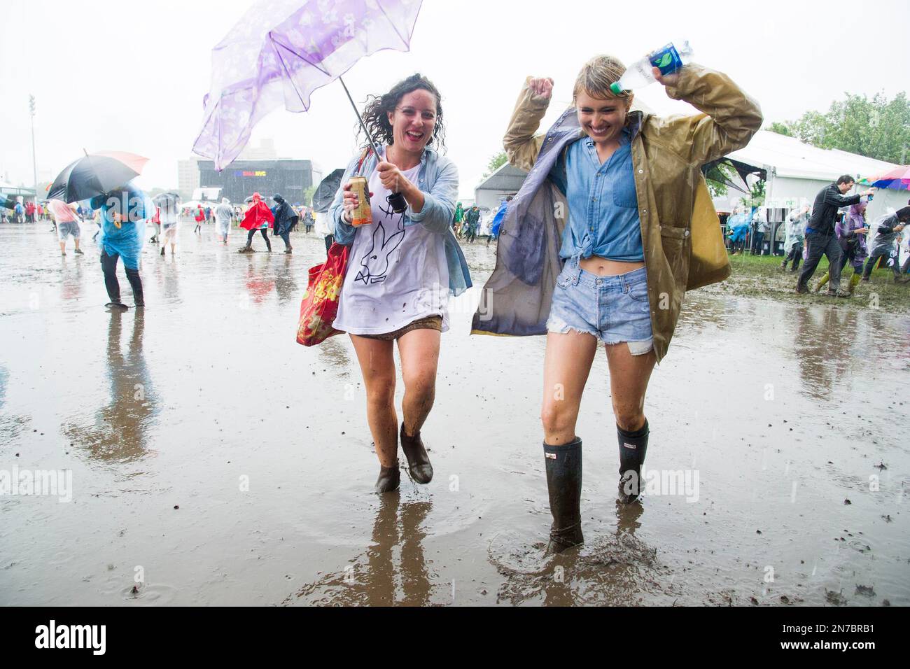Concertgoers walk through a field of mud at the rain-soaked 3rd annual ...