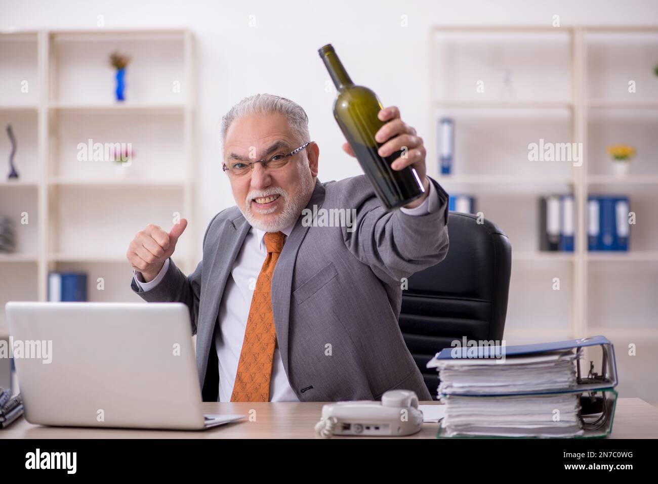 Old employee drinking alcohol at workplace Stock Photo - Alamy