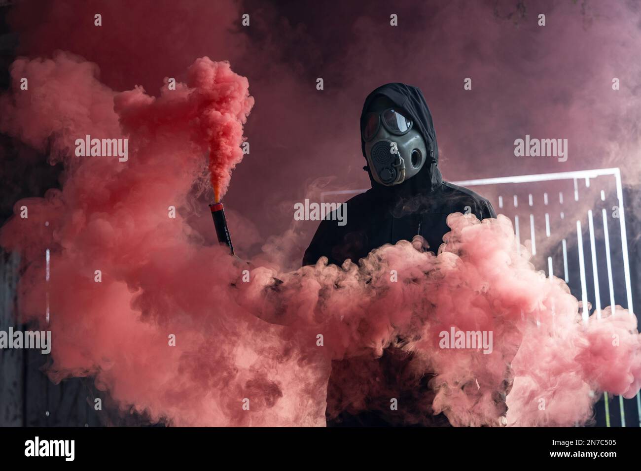 A man in gas mask holding a smoke bomb. Bright red colorful smoke. Old ...