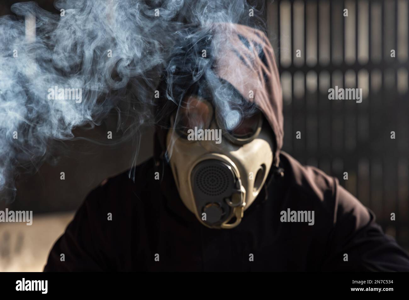 A man in gas mask holding a smoke bomb. Bright red colorful smoke. Old ...