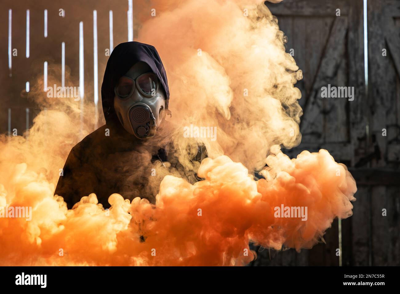 A man in gas mask holding a smoke bomb. Bright orange colorful smoke ...