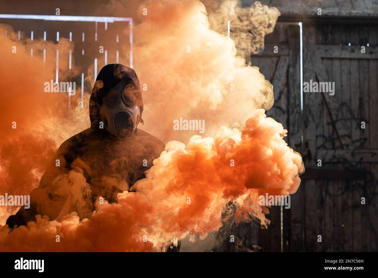A man in gas mask holding a smoke bomb. Bright orange colorful smoke ...
