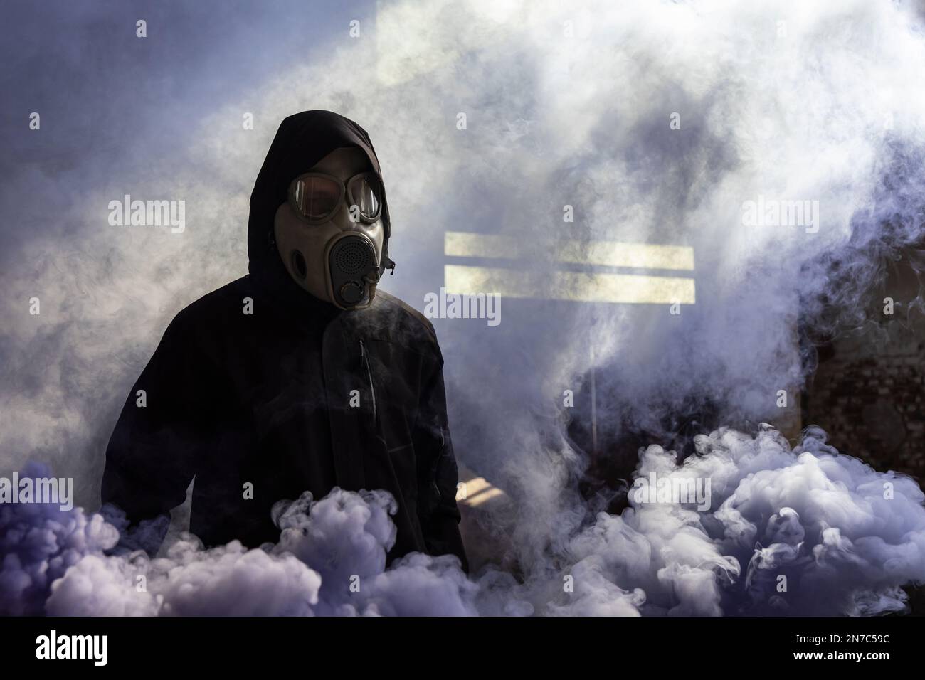 A man in gas mask holding a smoke bomb. Bright purple colorful smoke ...