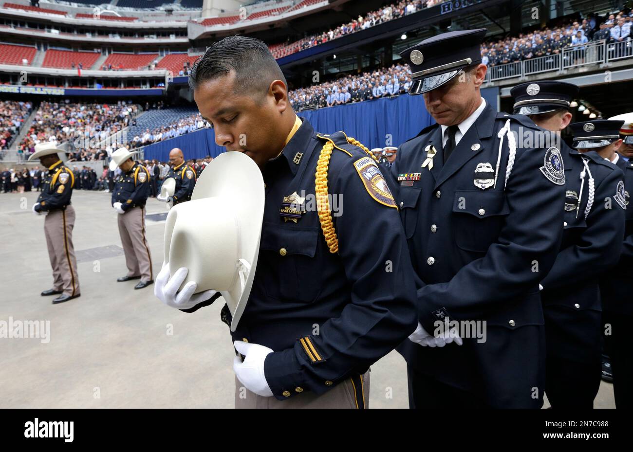 Law officers and firefighters bow their heads during a memorial service for fallen Houston ...