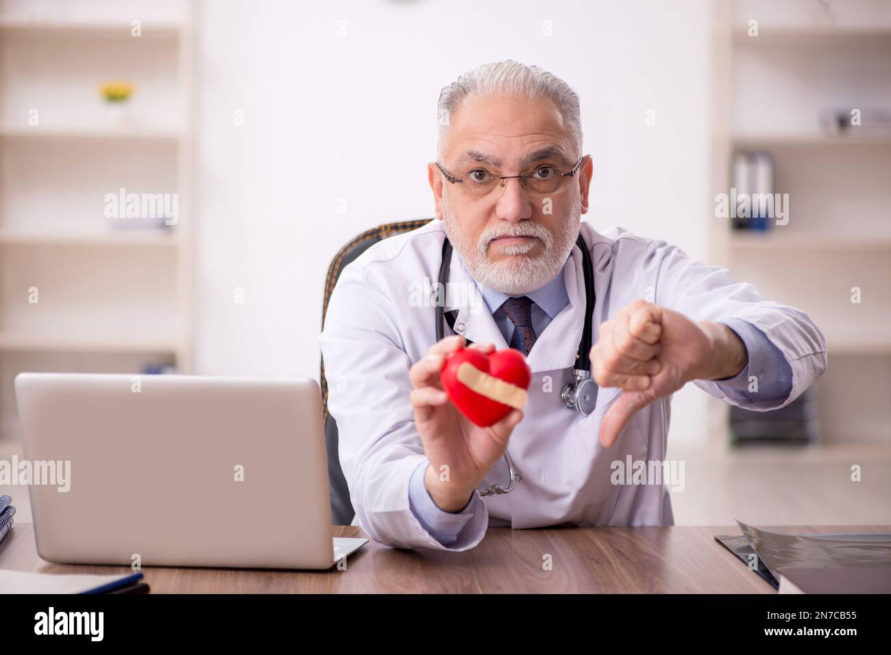 Old cardiologist holding heart model Stock Photo - Alamy