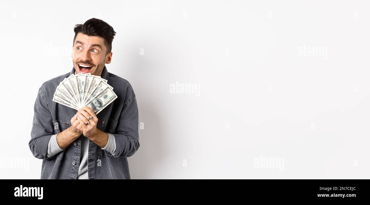 Rich happy man dreaming of shopping wish dollar bills in hands, looking ...